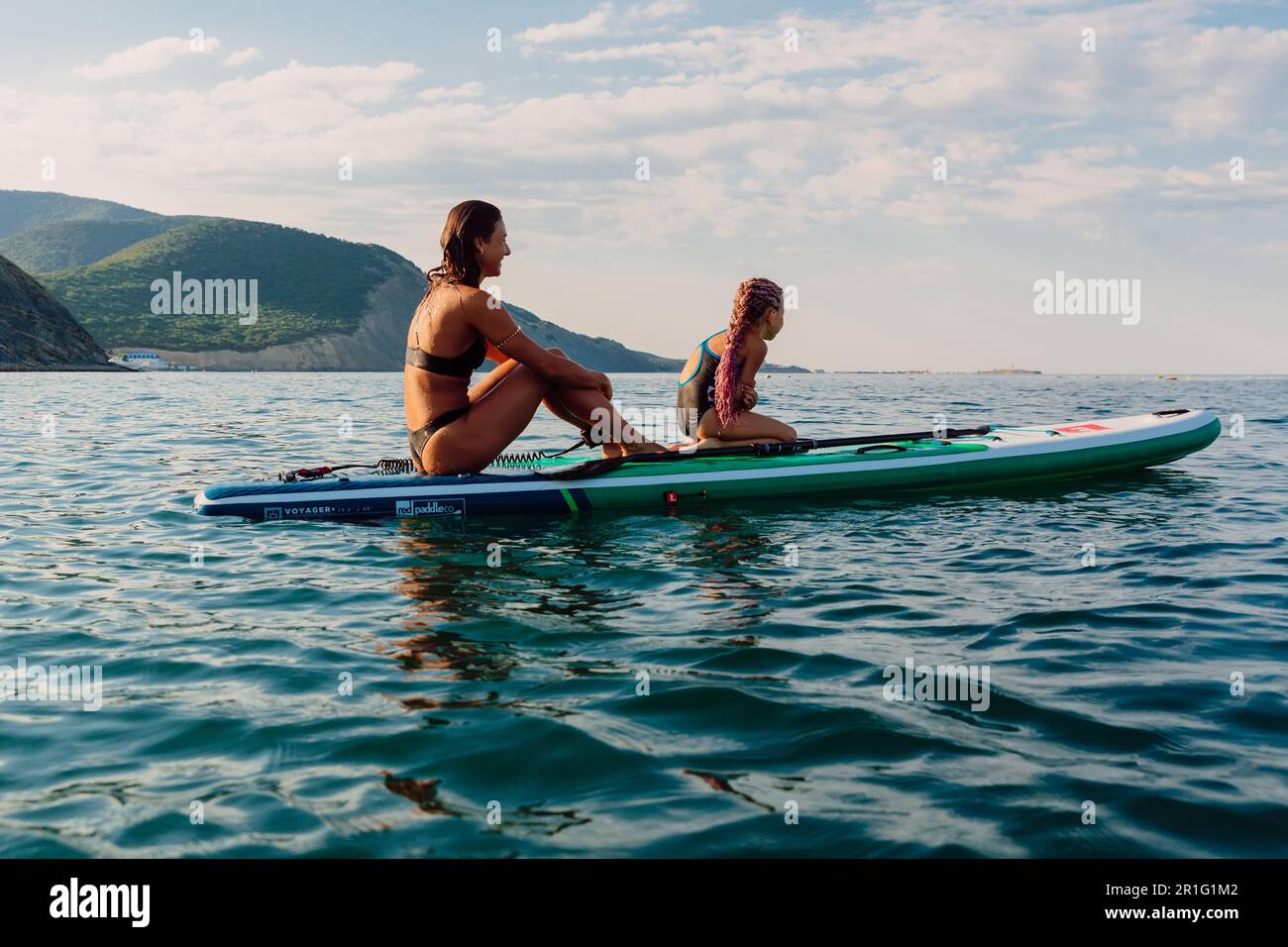 24. Juli 2022. Antalya, Türkei. Schlanke Frau mit einem Kind, das auf einem Stand-Up-Paddle ...