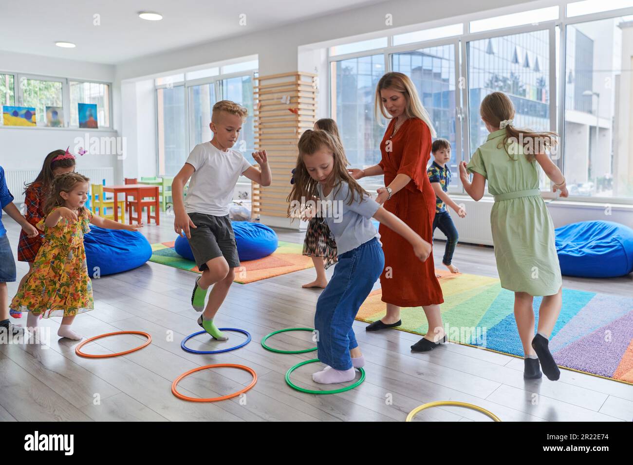Kleine Kinder im Kindergarten mit Lehrerin auf dem Boden drinnen im ...