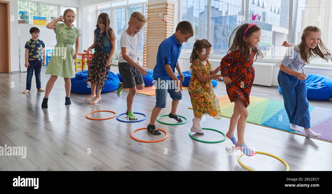 Kleine Kinder im Kindergarten mit Lehrerin auf dem Boden drinnen im ...