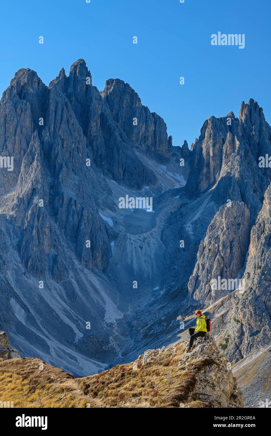 Frau, die auf einem Vorsprung sitzt, Cadini-Gruppe im Hintergrund, auf ...