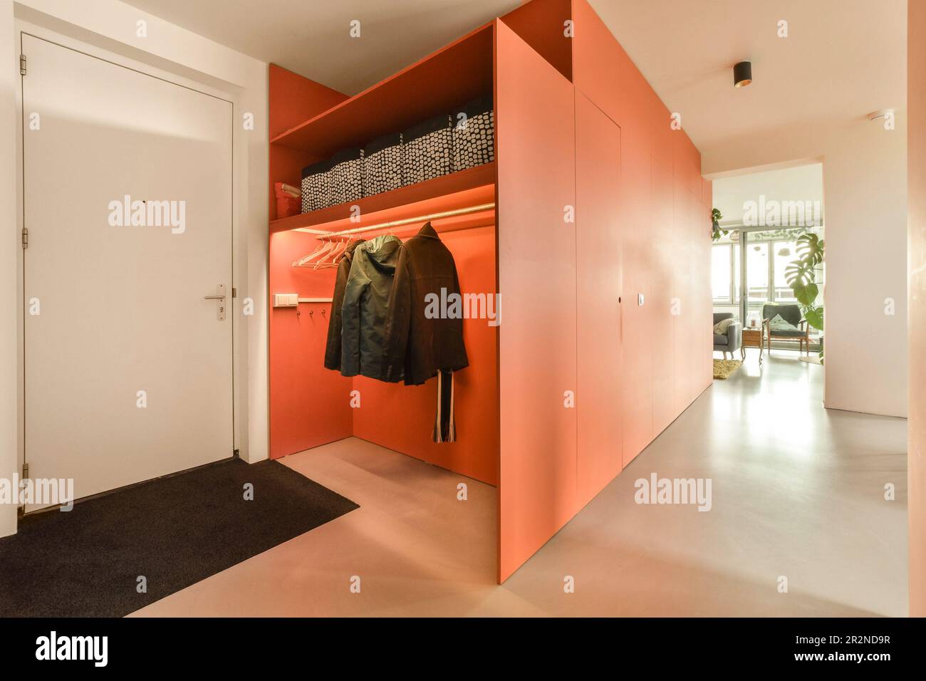 Ein begehbarer Kleiderschrank mit Kleidern, die an der Wand hängen, und ...