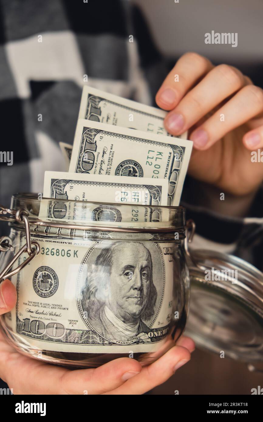 Dollar-Banknote, die Geld im Glasbehälter spart. Nicht wiedererkennbare ...