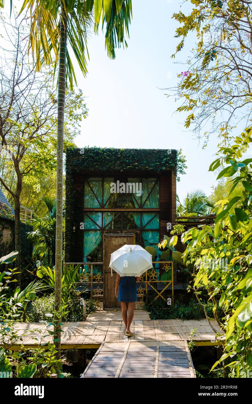 Asiatische Frauen gehen mit einem Schirm in einem hölzernen Cottage ...