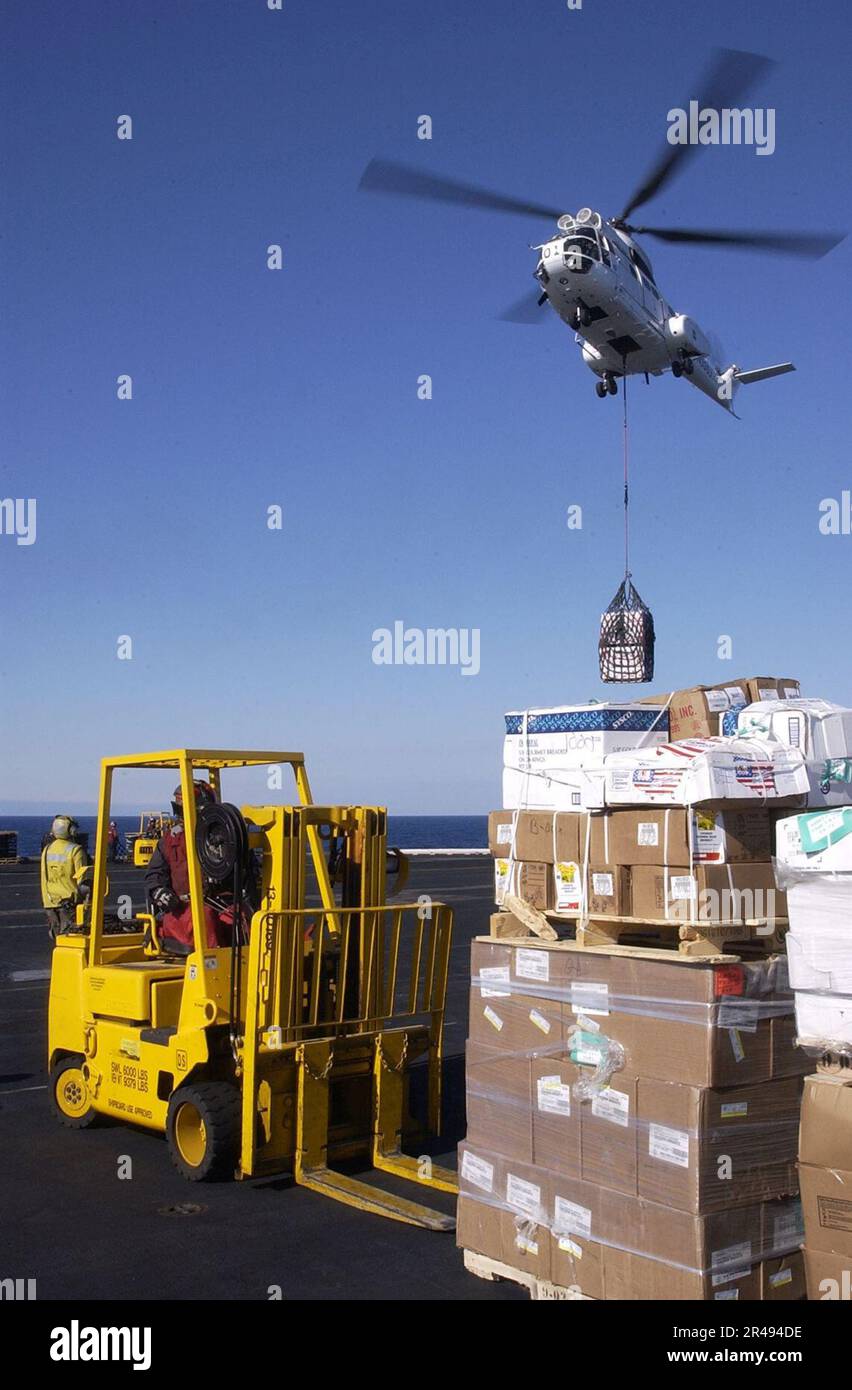Mitarbeiter DES US Navy Flightdeck positionieren Fracht mit Gabelstaplern wie ein SA-332 Super ...