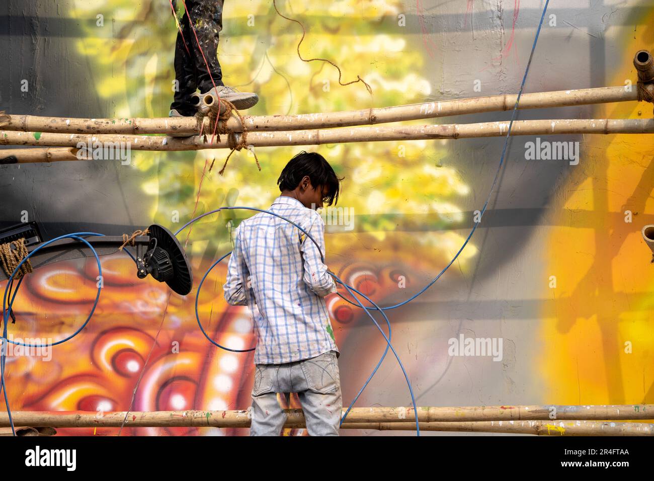 Ein Mann, der auf einem Bambusgerüst steht und mit einer ...