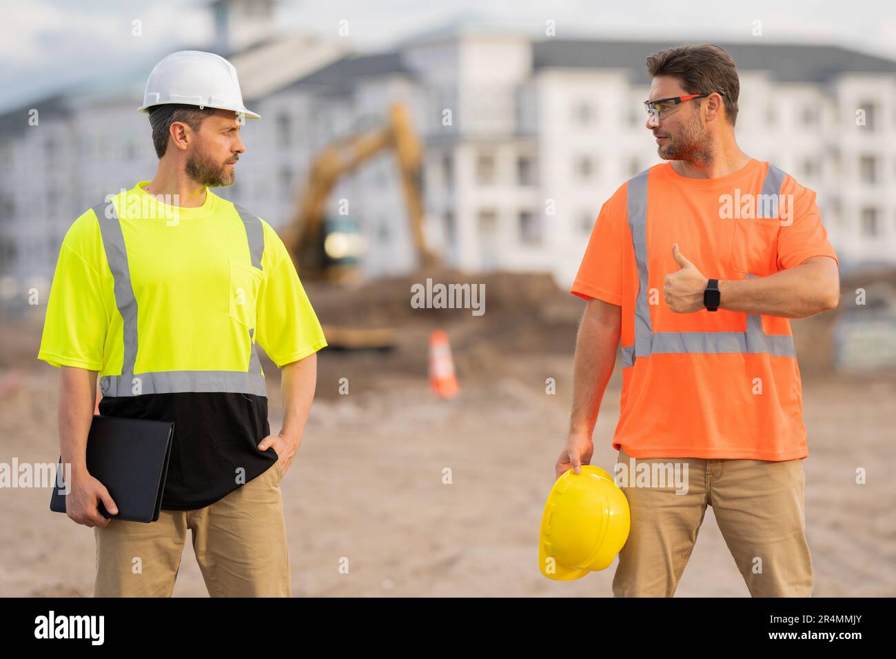 Zwei Bauunternehmer mit Schutzhelm arbeiten an einem Bauprojekt auf ...