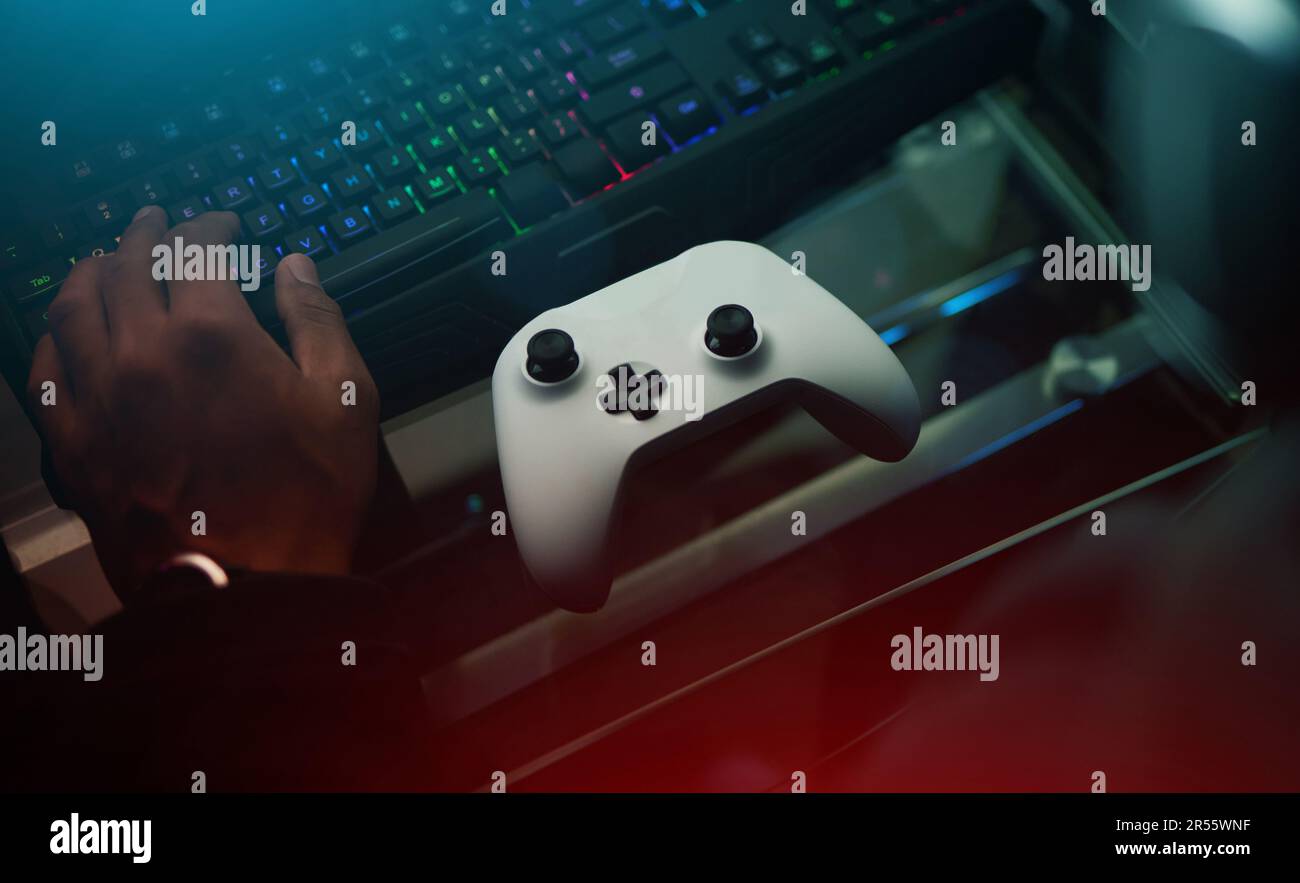 Hand, Videospiel-Controller und Tastatur auf dem Schreibtisch ...