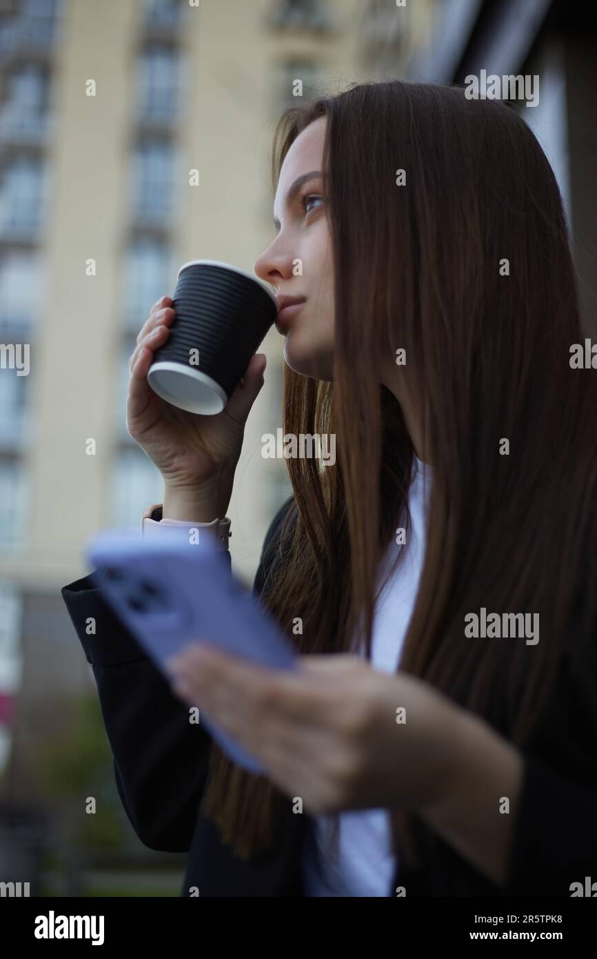 Junge Frau, die einen Schluck Kaffee in einem Café trinkt. Porträt einer schönen Frau, die ...