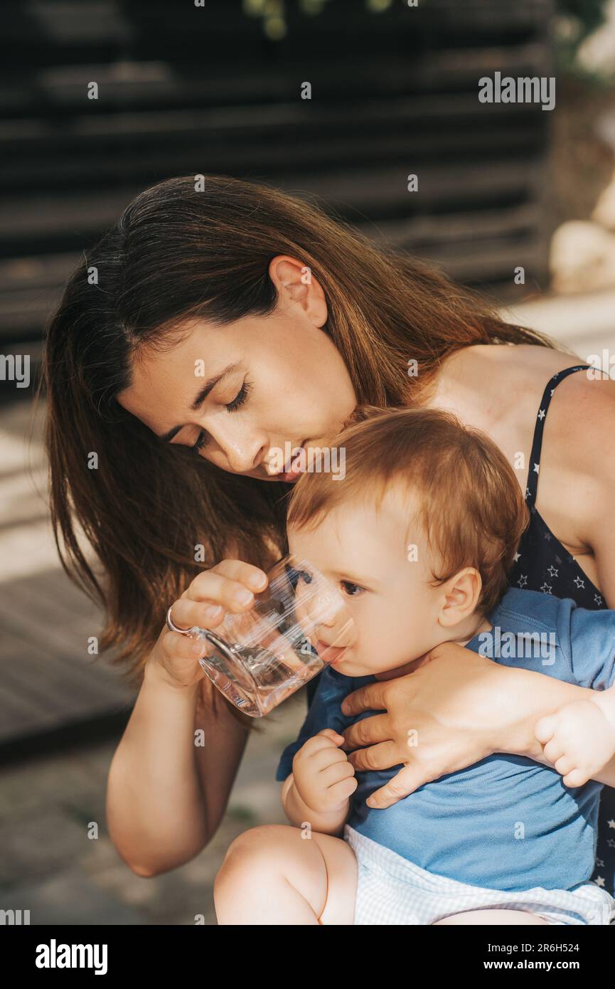 Mutter und Baby im Café im Freien, mutter gibt dem Kind Wasser aus ...