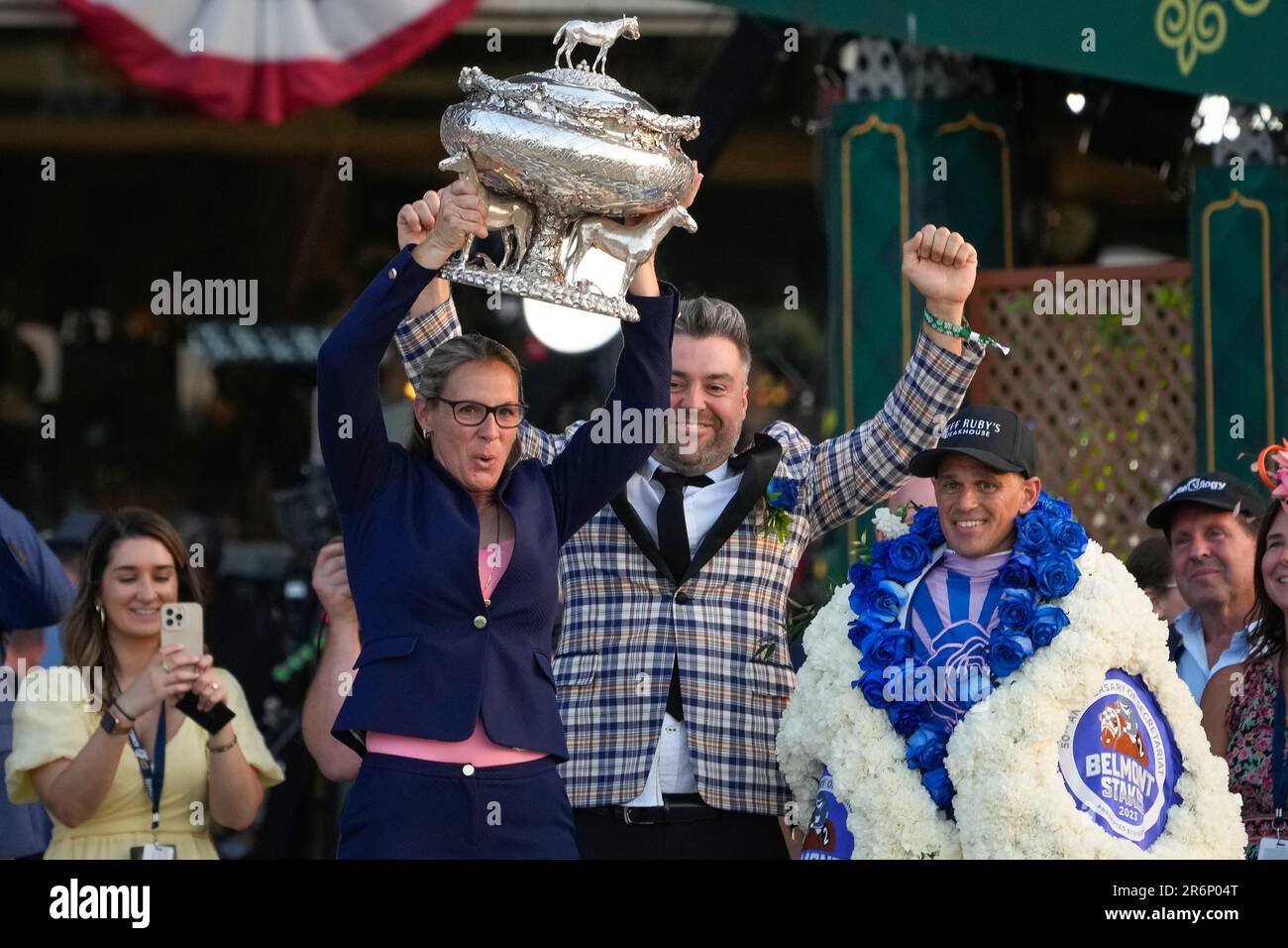 Trainer Jena Antonucci, left, hoists up the August Belmont Trophy ...
