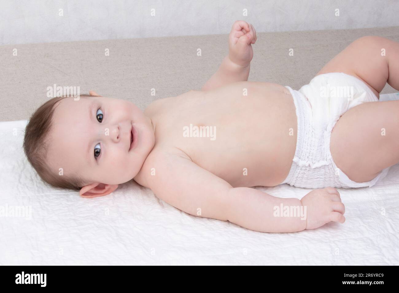Ein sechs Monate alter Junge in einer Windel liegt auf einer Windel. Das Konzept von ...