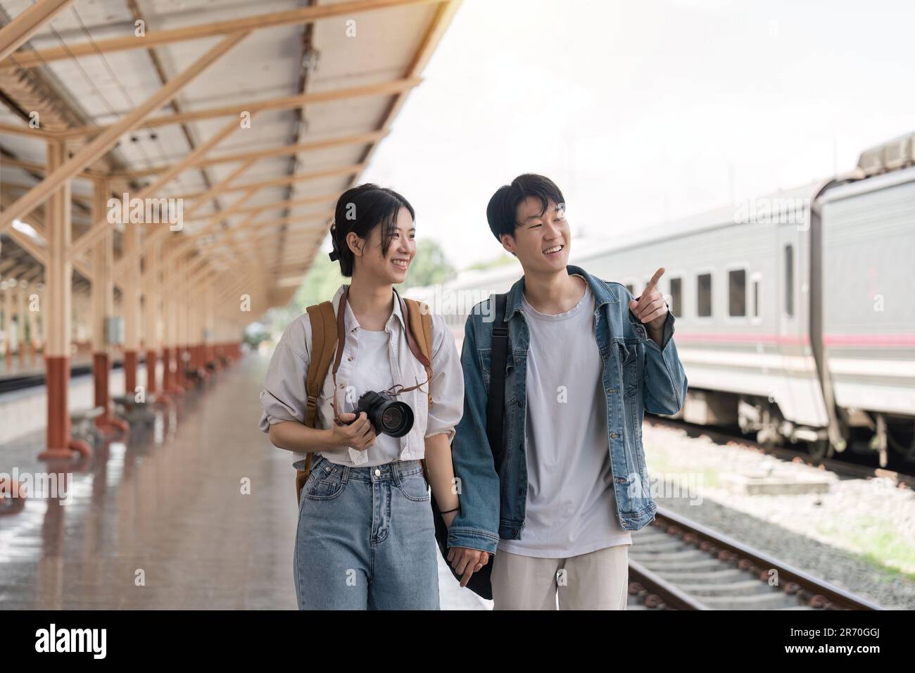Wunderschönes Paar am Bahnhof, das auf den Zug wartet. Junge Frau und Mann warten darauf, in ...