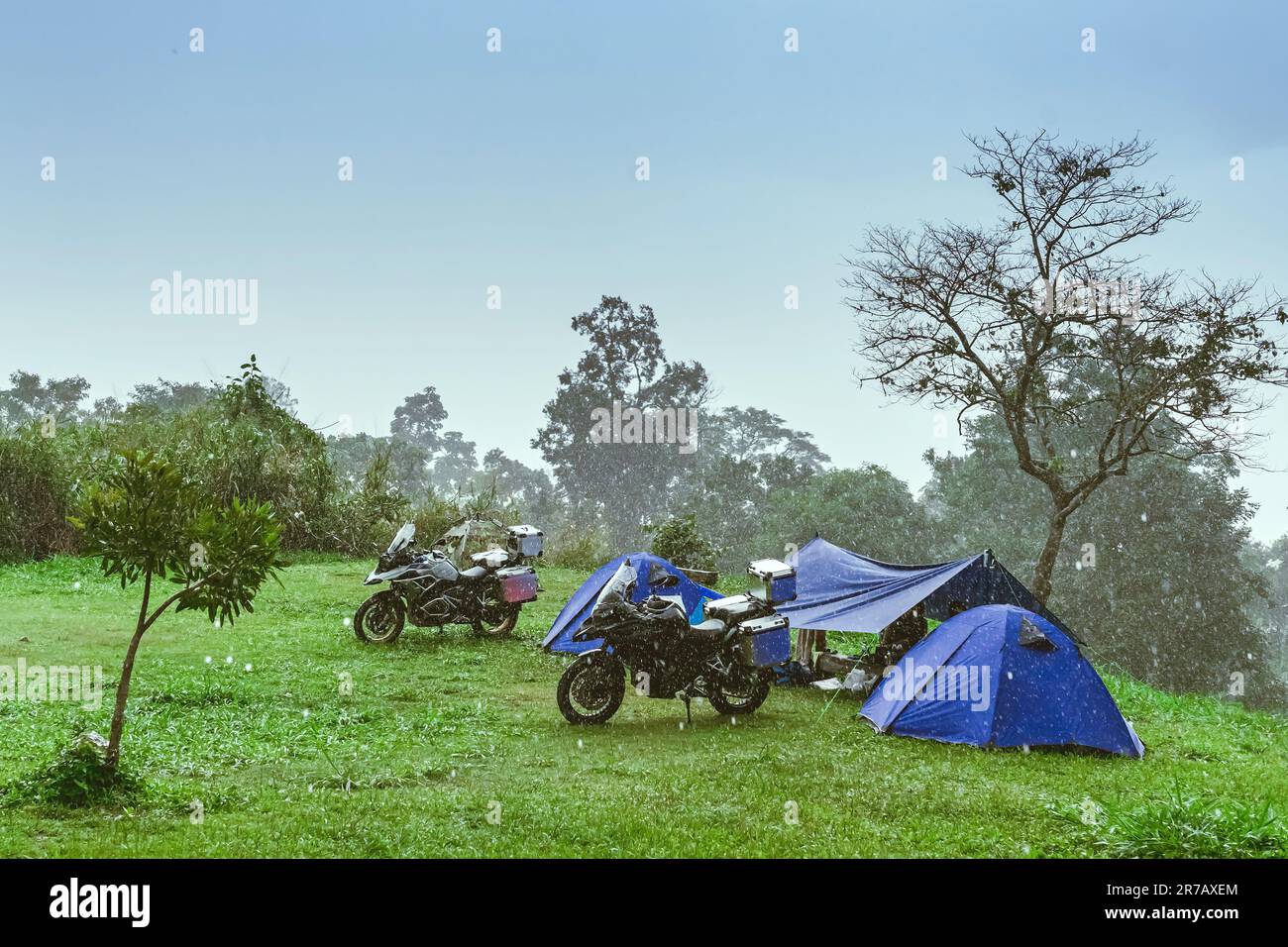 Motorrad mit Regen. Campingaktivität im regenreichen Urlaub. Zelt auf dem Campingplatz am Hügel ...