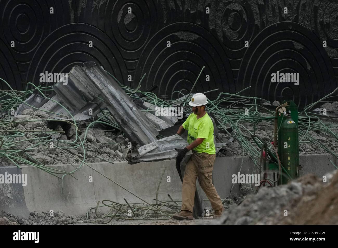 A construction worker move debris at the scene of a collapsed elevated ...