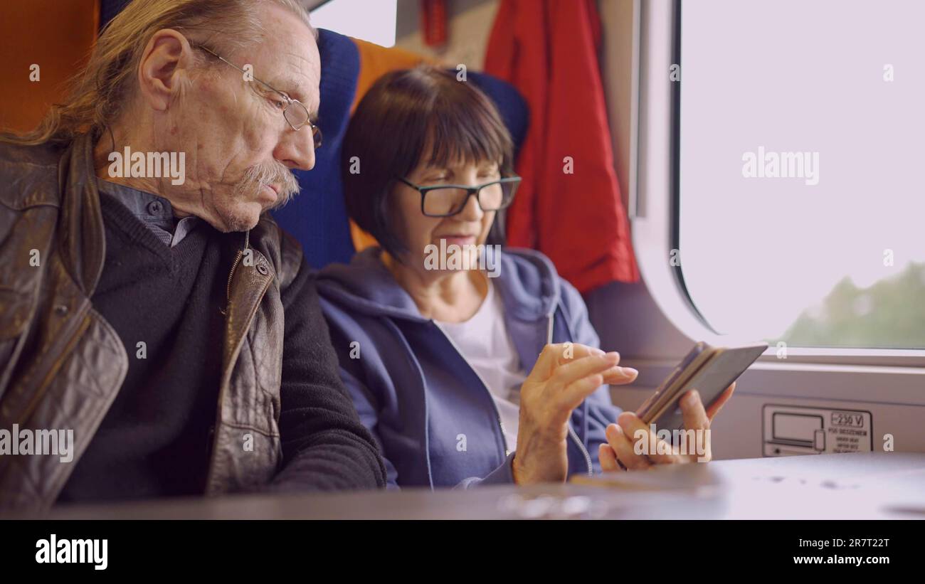 Ältere Paare Fahren Mit Dem Zug Die Dame Hält Ein Handy In Der Hand Beide Schauen Auf Das
