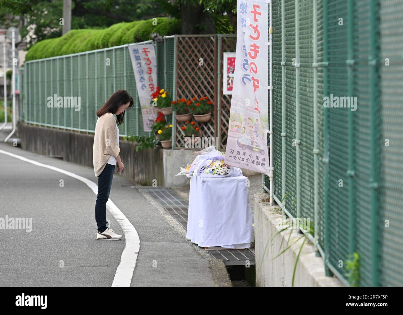 A woman offers prayers and a bunch of flowers for a nine-year-old girl Rina Miyake, a fourth ...