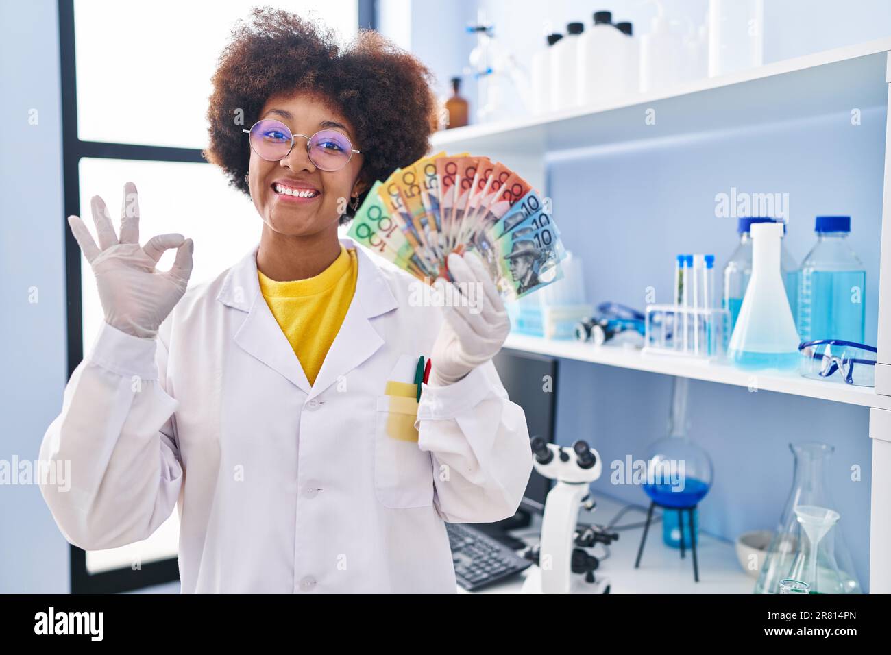 Junge afroamerikanische Frau, die im Labor arbeitet und Geld hat, mit ...