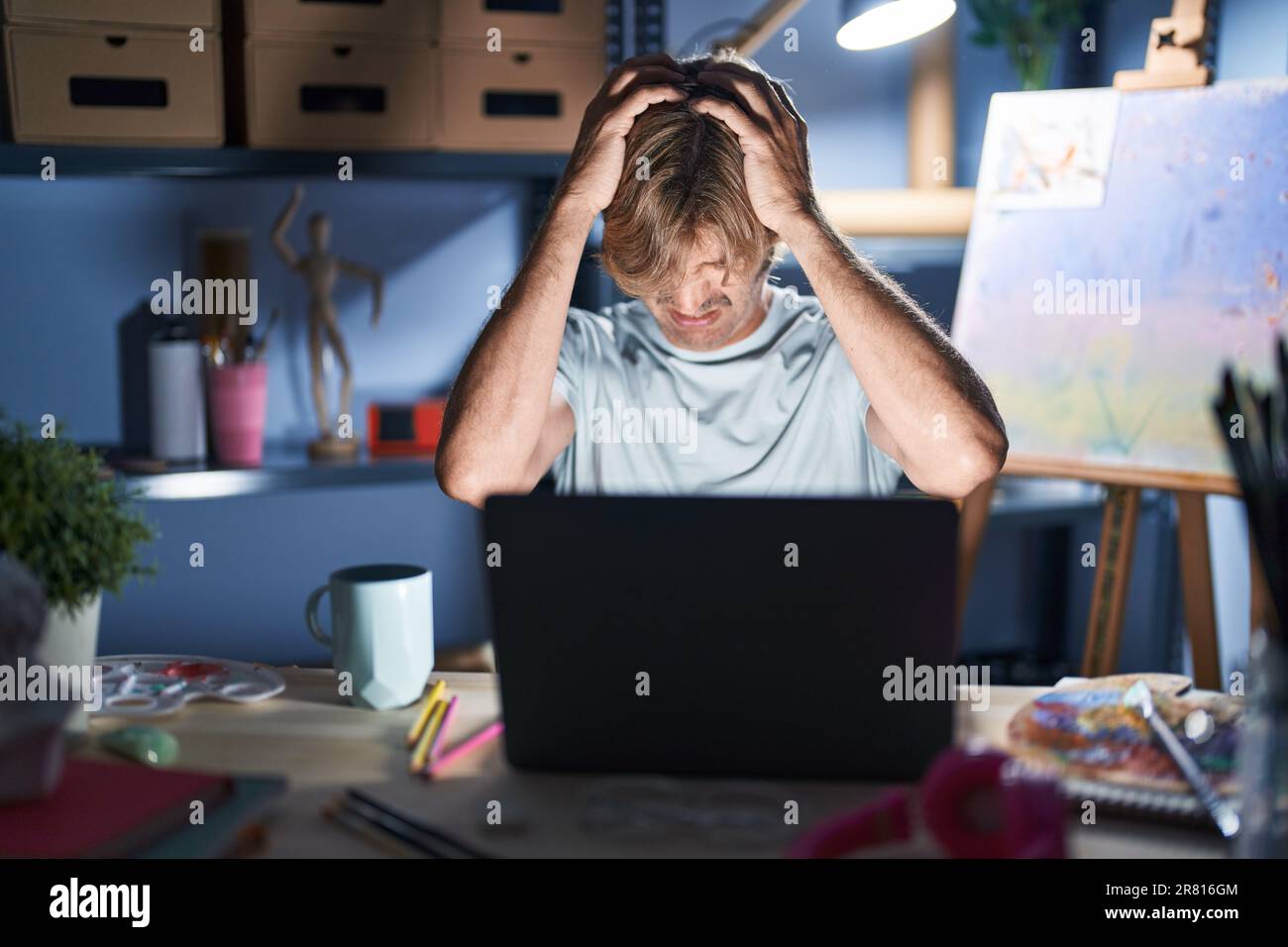 Ein Mann mittleren Alters, der nachts mit einem Laptop im Kunststudio ...