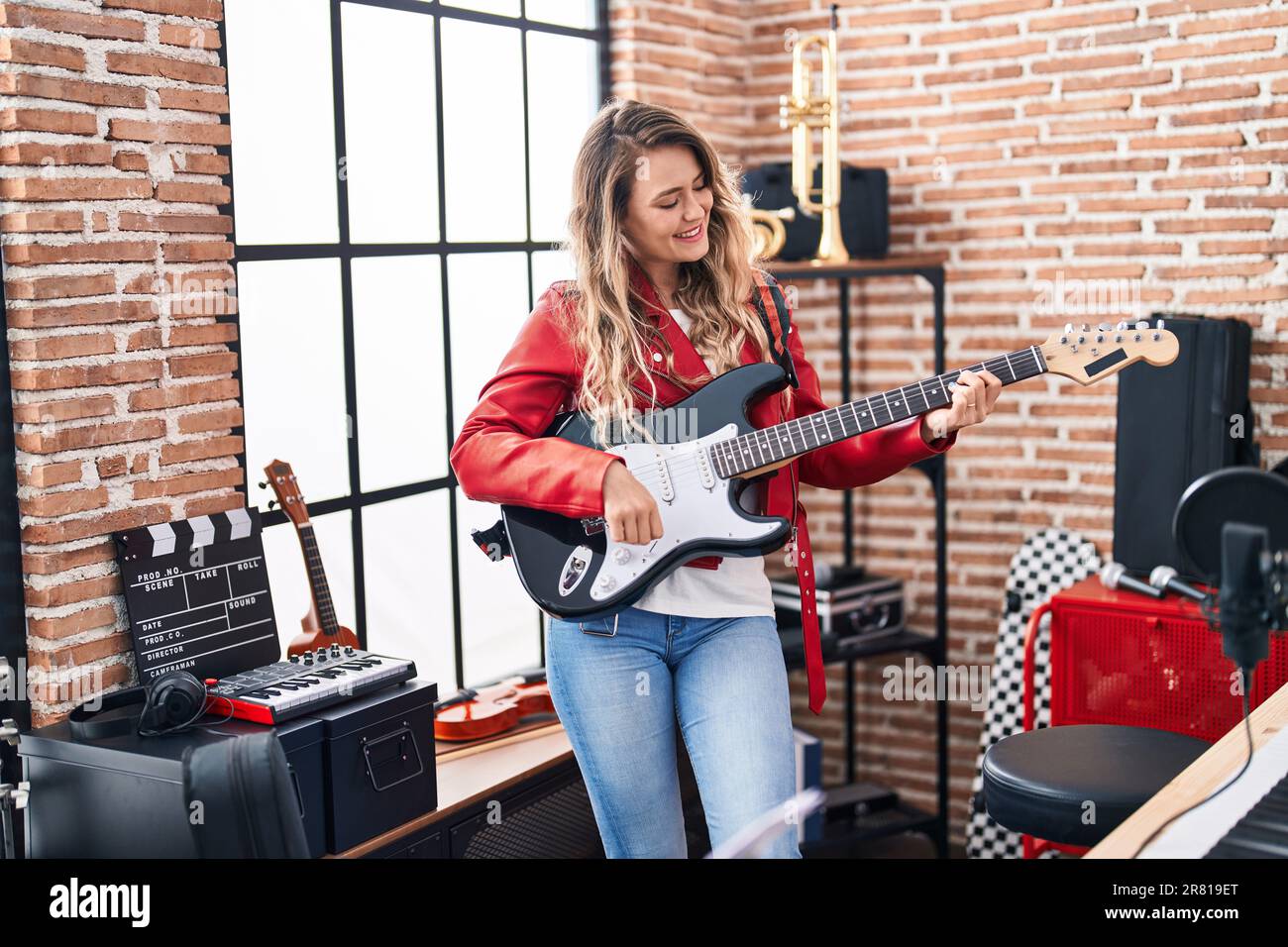 Junge Musikerin, die im Musikstudio elektrische Gitarre spielt ...
