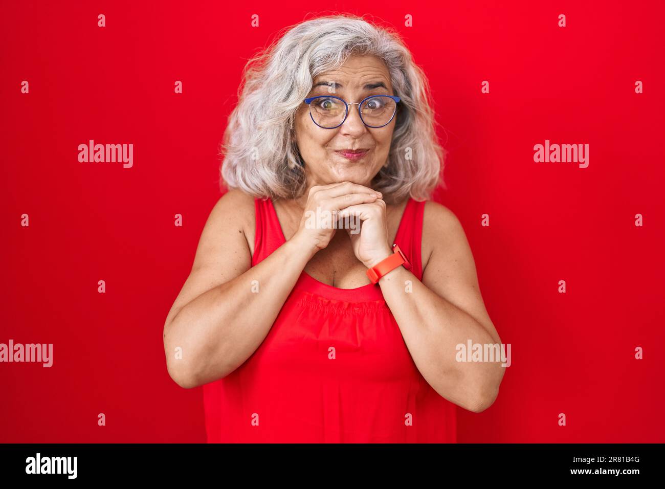 Eine Frau mittleren Alters mit grauen Haaren, die über einem roten ...