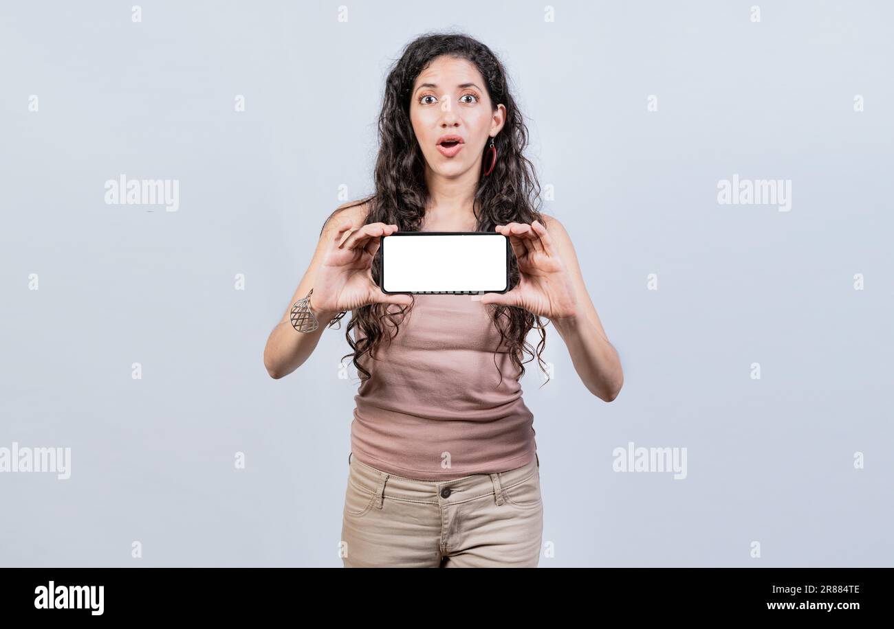 Überraschendes Mädchen, das einen leeren Bildschirm mit Smartphone zeigt. Ein lateinisches ...