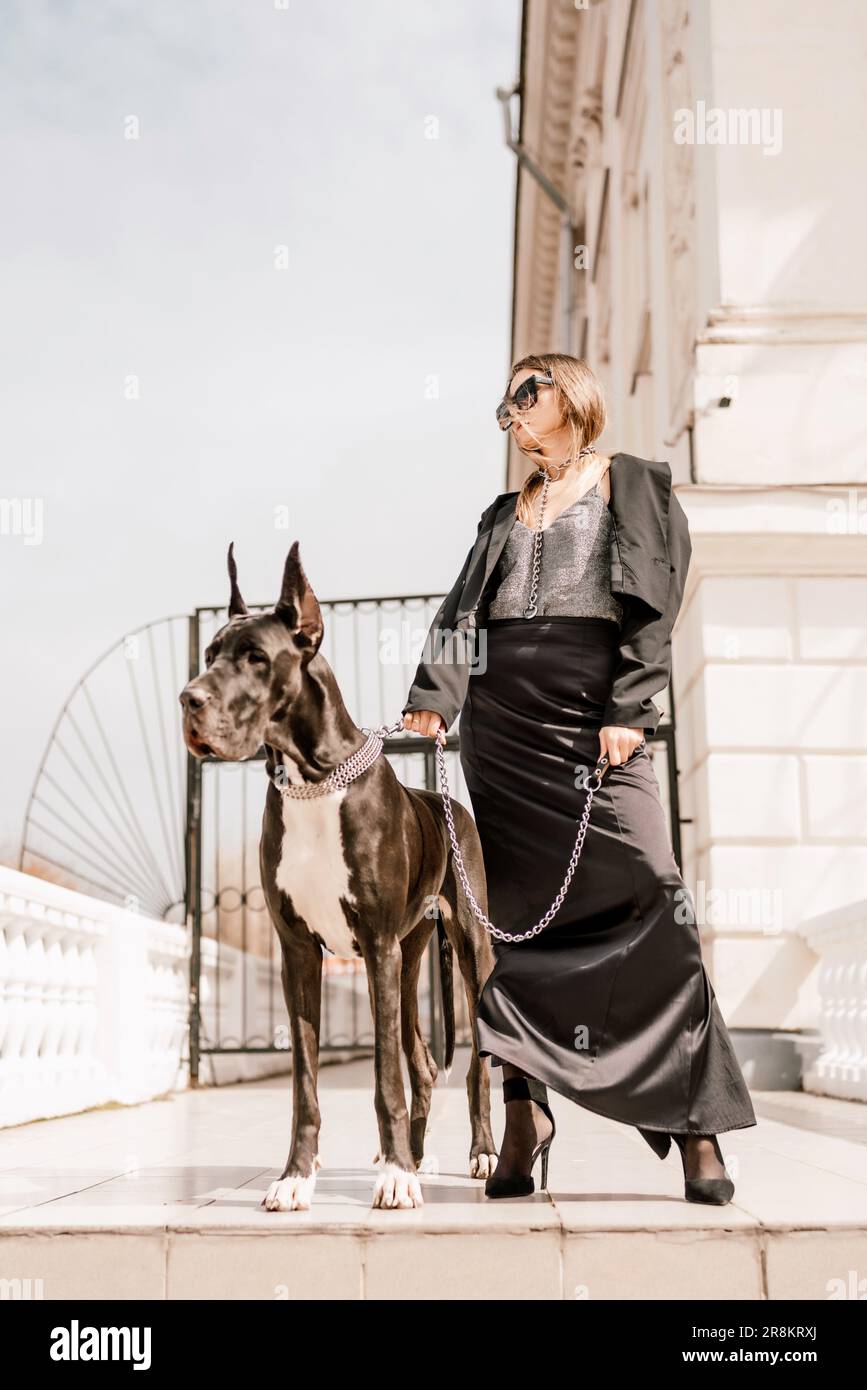 Eine Frau geht mit ihrer Dogge in einer urbanen Umgebung spazieren und ...