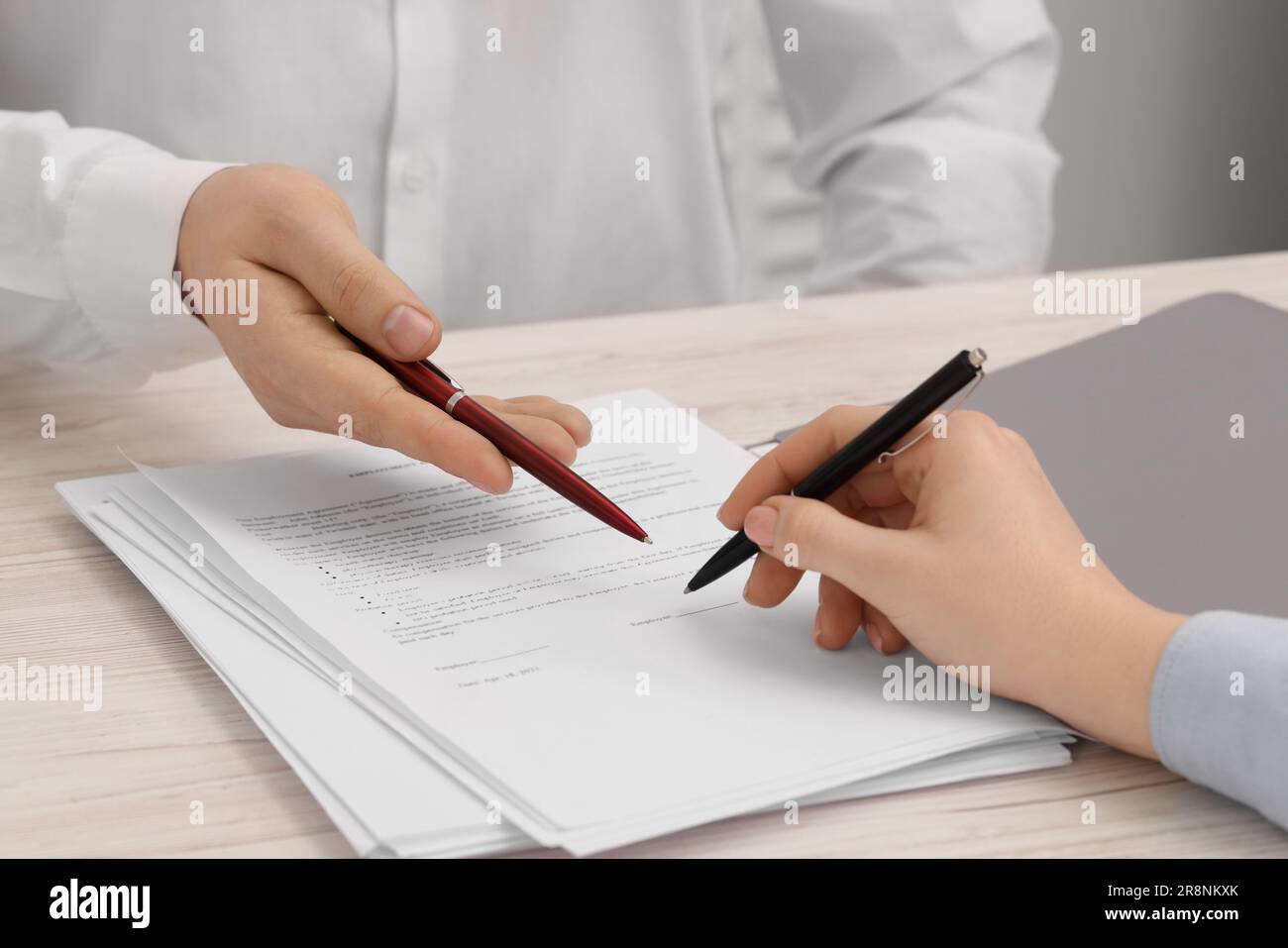 Ein Mann zeigt auf ein Dokument und eine Frau legt Unterschrift auf ...