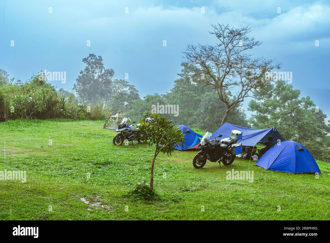 Motorrad mit Regen. Campingaktivität im regenreichen Urlaub. Zelt auf dem Campingplatz am Hügel ...