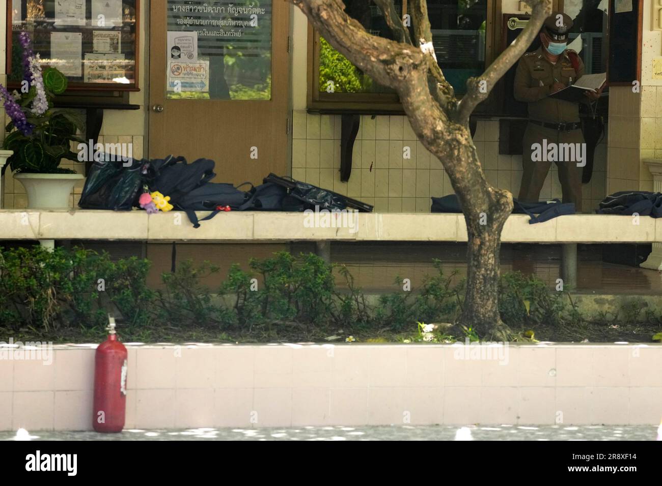A Thai police officer stands behind at an explosion site in a high ...