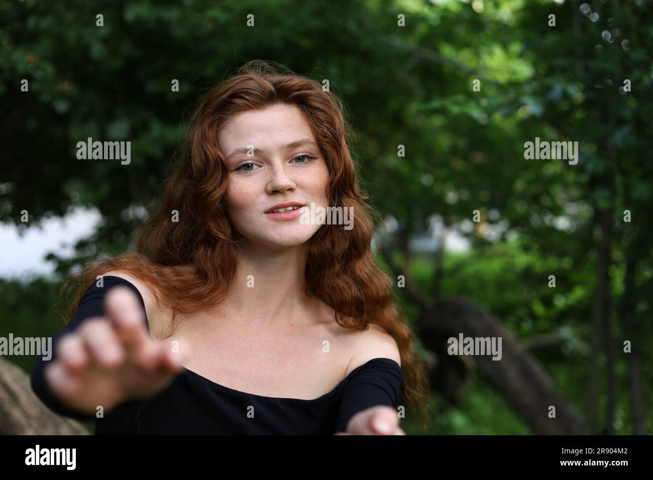 Porträt eines lächelnden Ingwermädchens mit langen roten Haaren und Sommersprossen, das ihre ...