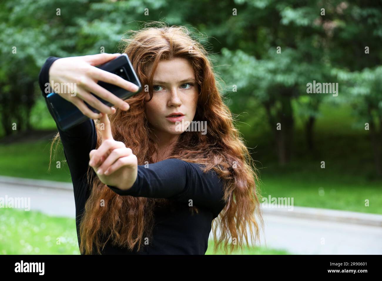 Verführerisches Mädchen mit langen roten Haaren, das Selfie mit einer Smartphone-Kamera im ...