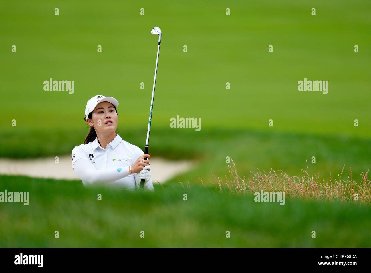 Xiyu Lin, of China, watches her shot out of a bunker on the fifth hole ...