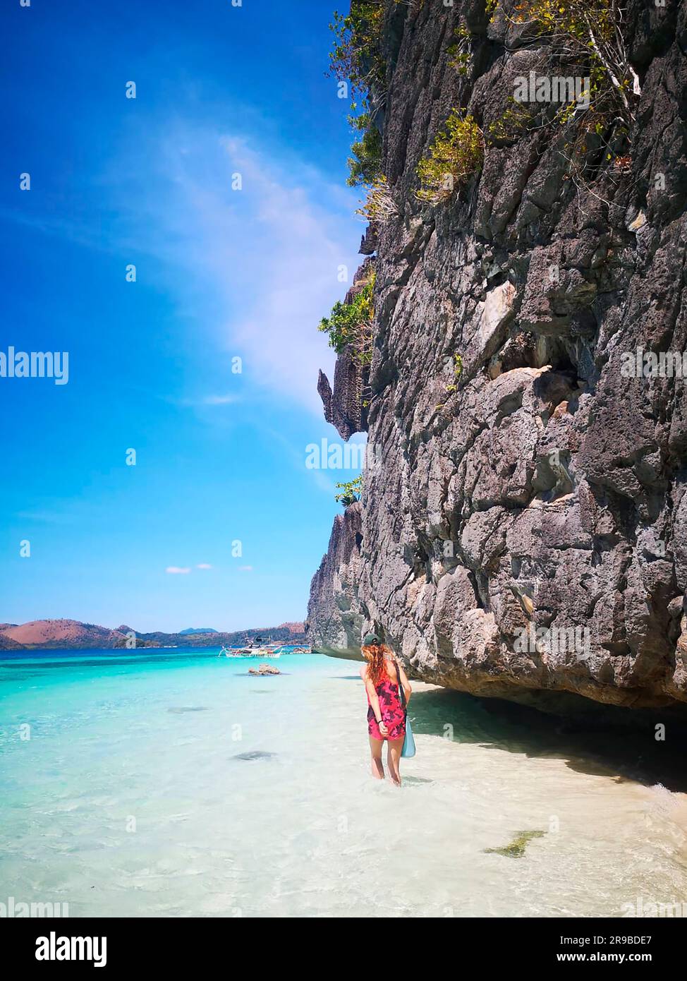 Eine junge Frau läuft aufregend am Strand entlang mit zerklüfteten ...
