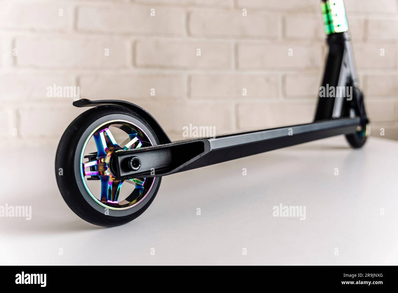Das Hinterrad und die Bremse eines Stunt Rollers mit regenbogenfarbenen ...