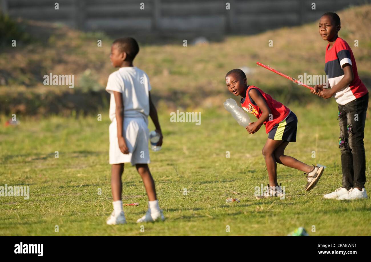 Children play a game of cricket using plastic bottles and sticks at ...