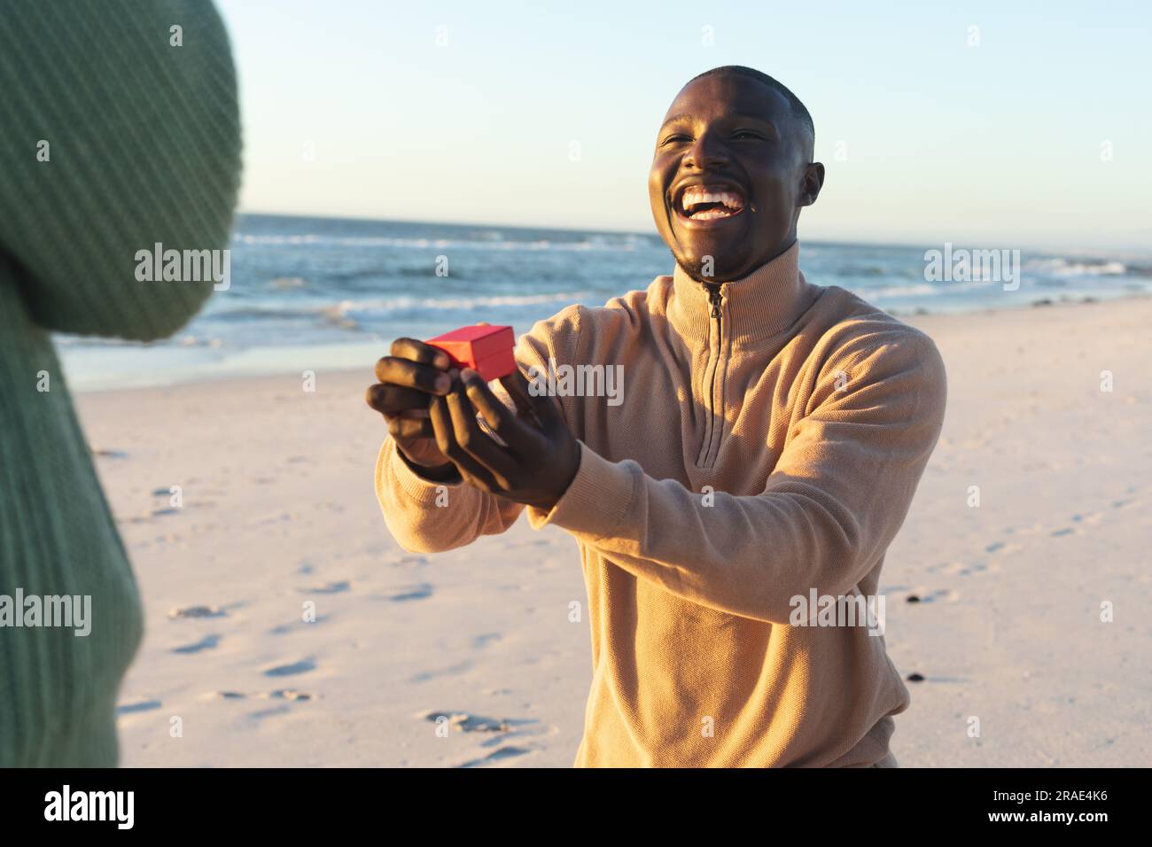 Ein glücklicher afroamerikanischer Mann kniete mit dem Ring und machte ...
