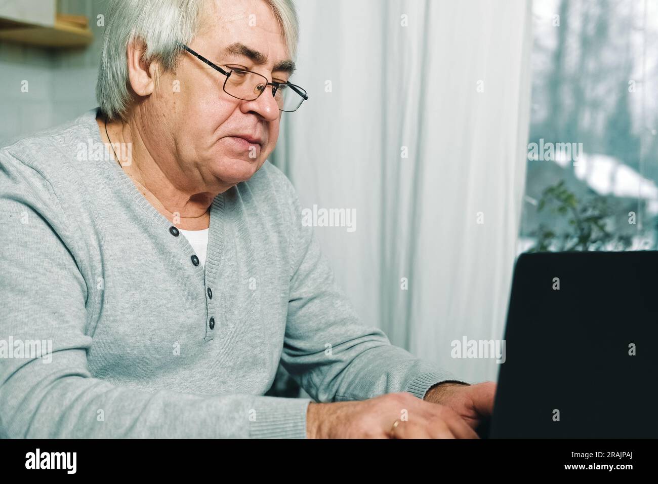 Ein alter Mann, der an ein Notebook denkt. Pensive Mature Grey hair 60s ...