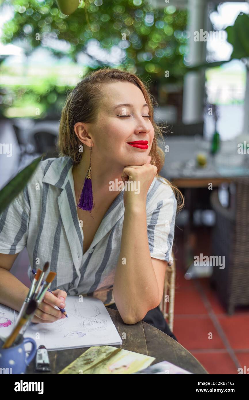 Eine wunderschöne blonde Künstlerin und Illustratorin, die über ein Konzept ihrer Zeichnung ...