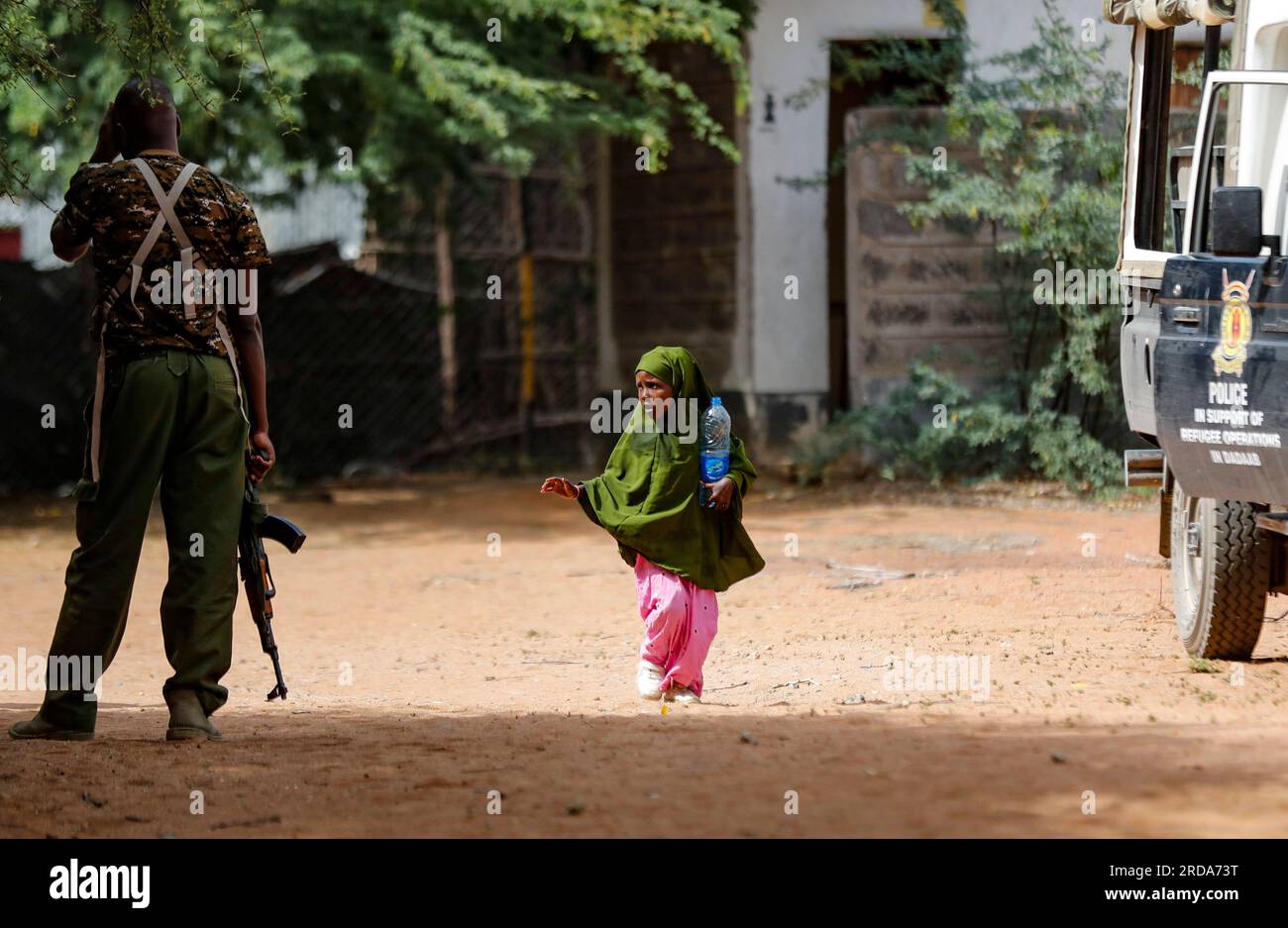 A Somali refugee girl walks past an armed Kenyan policemen outside a ...