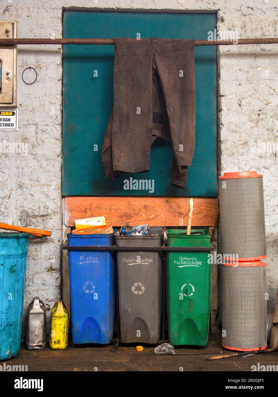 Eine dreckige Müllecke in einer Autowerkstatt mit drei Plastikbehältern ...