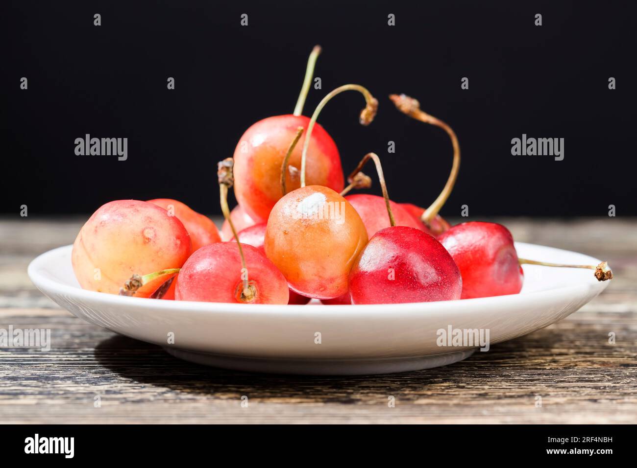Verfaulte Kirschen auf einem Holztisch, ein paar Beeren, die bereits ...