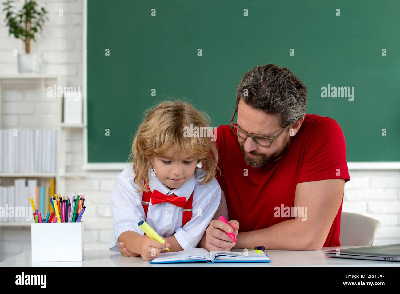 Grundschuljunge im Klassenzimmer im Unterricht. Der Lehrer erklärt dem ... Grundschuljunge im Klassenzimmer im Unterricht. Der Lehrer erklärt dem ...