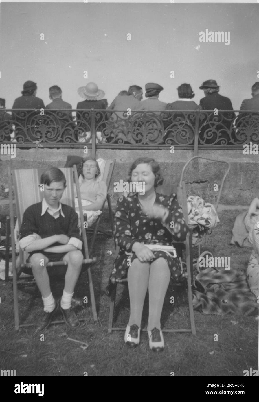 Eine Familie am Strand am Meer, die in Liegestühlen an der Uferwand ...