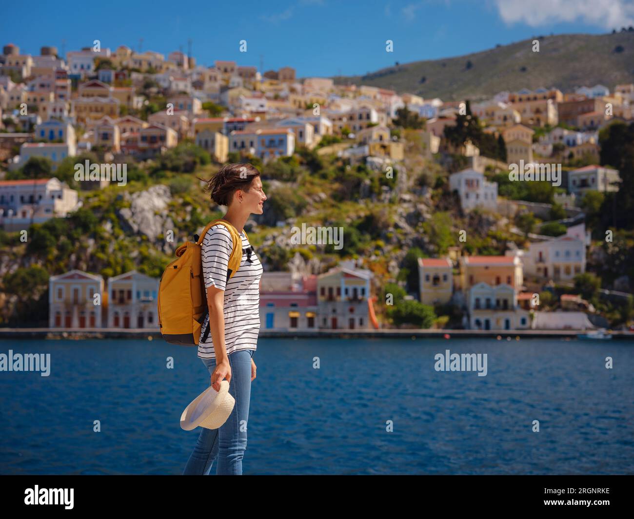 Schöne asiatische glückliche Frau mit Rucksack, die ihren Urlaub auf den Symi-Inseln genießt ...