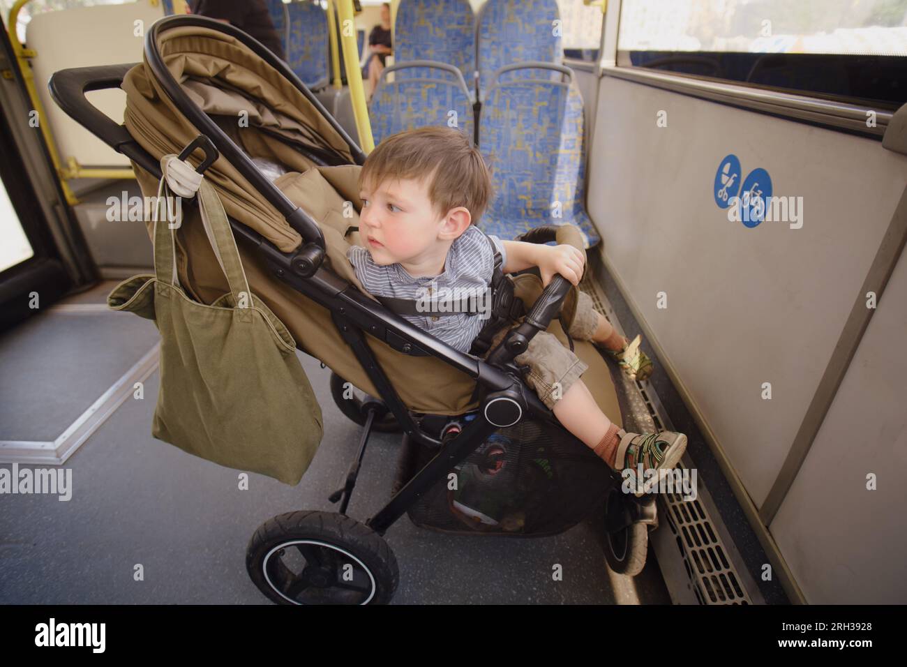 Das Baby sitzt in einem Buggy im Bus und genießt die Mobilität und den ...
