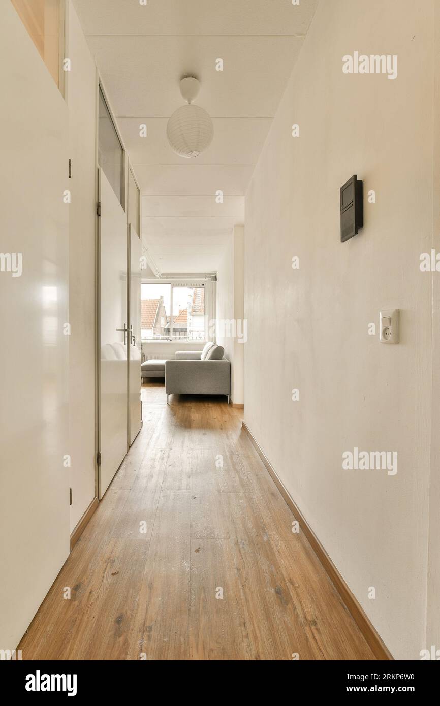 Ein langer Flur mit Holzfußboden und weißen Wänden auf beiden Seiten ...