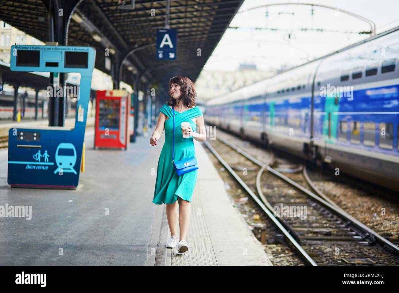Junge Frau in Paris, die auf einen Zug am Bahnhof wartet. Örtlicher französischer Pendler, der ...