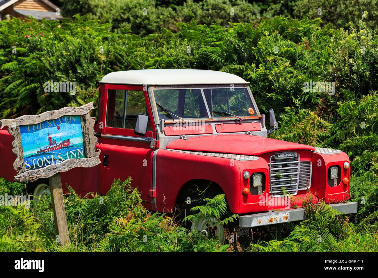 Rotes Oldtimer-Auto, Land Rover in Büschen, Schild Werbung Pub ...