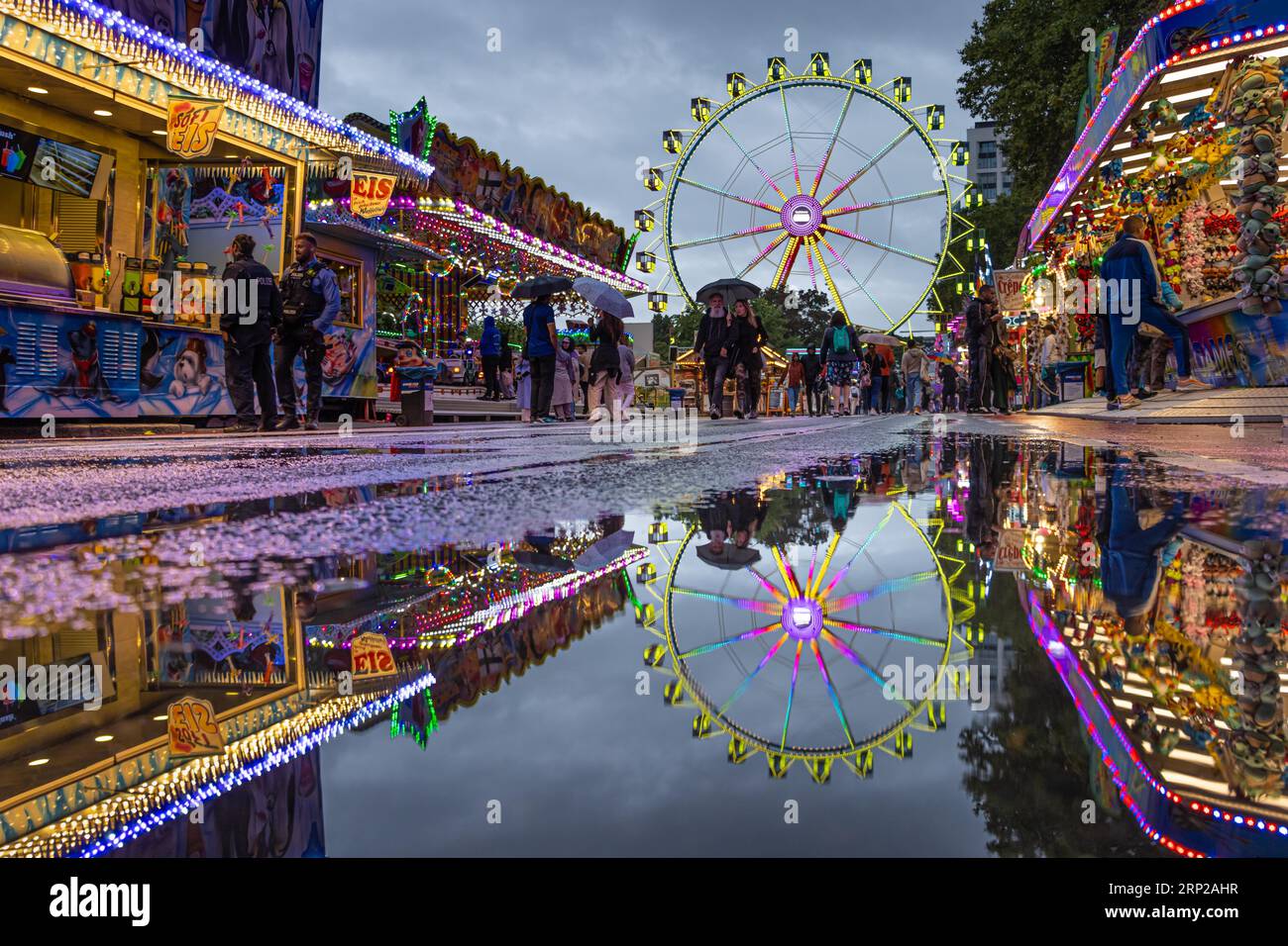 Die bunten Lichter des Mainfestes spiegeln sich in einer Pfütze wider ...