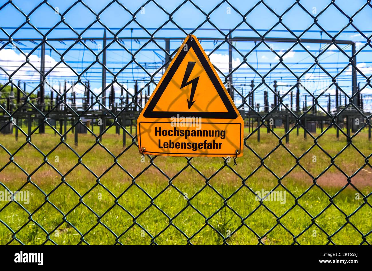 Schild mit den Worten Hochspannung in deutscher Sprache am Zaun Einer ...